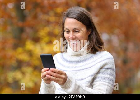 Middle age woman using smartphone sitting on bed at bedroom Stock Photo ...