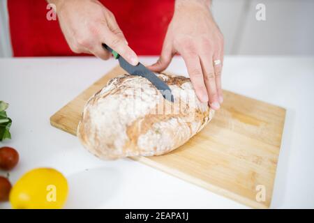 Male hands slicing bread on a cutting board Stock Photo - Alamy