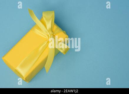 rectangular box with a gift wrapped in yellow paper and tied with a ...