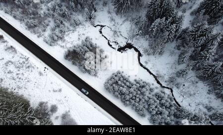 Aerial shot of a road through the snow-covered forest Stock Photo - Alamy