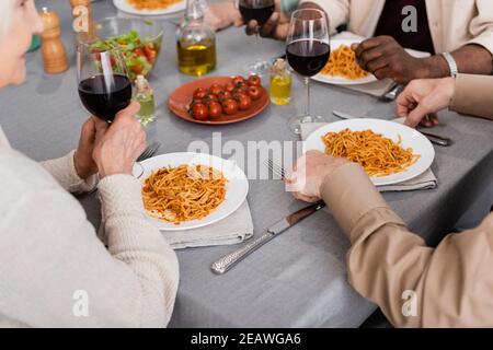 partial view of multicultural and senior friends having delicious lunch ...