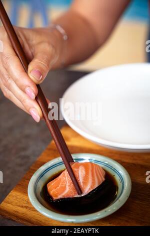 Salmon sashimi with soy sauce been picked up with chopsticks Stock ...