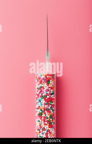 Syringe with colorful balloons on a pink background with free space ...