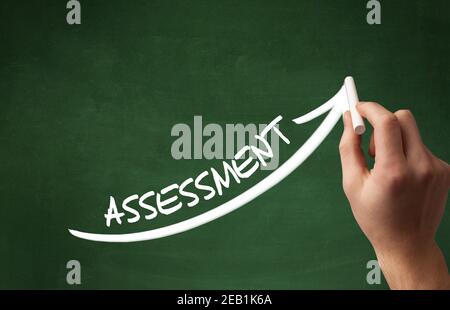 Hand drawing ASSESSMENT inscription with white chalk on blackboard ...