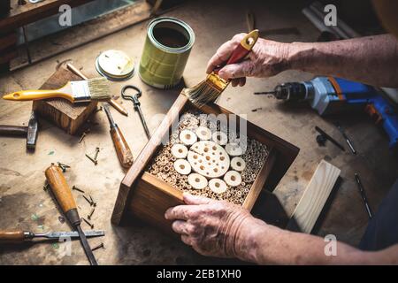 Painting wooden insect hotel in workshop. Making handmade insect house ...