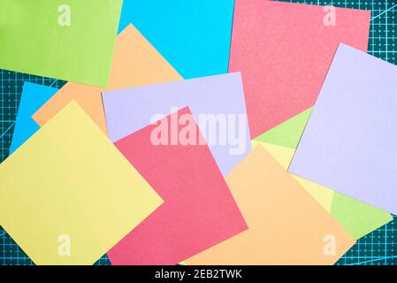 Colorful paper squares on a cutting board. Supplies for origami or ...