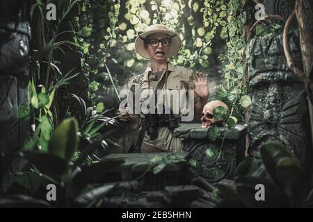 Scared explorer walking in the jungle and finding a human skull, she is ...