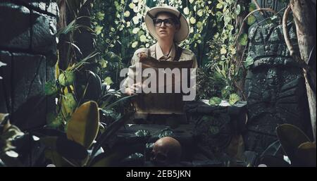 Scared explorer lost in the jungle: she is holding a map and looking at ...