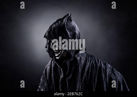 Vampire with cape showing his scary teeth over dark misty background ...