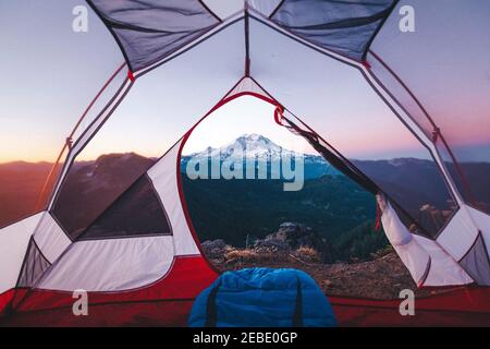 Serene view of a hiker with a tent on a cliff by the ocean enjoying the ...