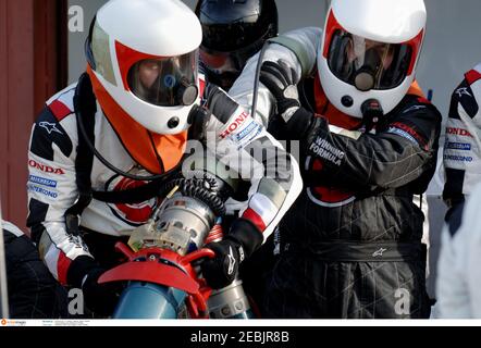 Pit crew refueling racing car with reflective helmet Stock Photo - Alamy