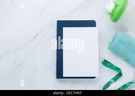 Blank white paper note and fitness equipments on white marble ...
