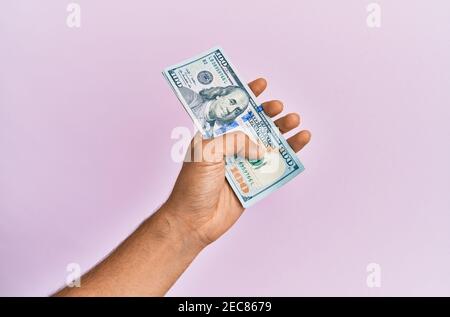 Hispanic hand holding usa dollars banknotes over isolated pink ...