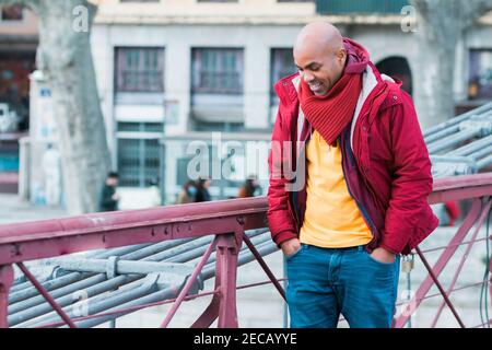 Bald Latin male in a red coat talking on his phone while walking in a ...