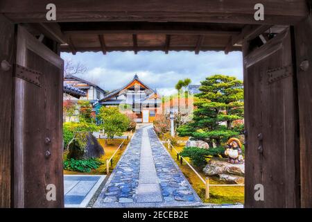 Entrance to traditional Japanese garden with stone path and tile roofed ...