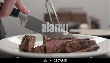 man slicing new york steak on white plate, wide photo Stock Photo - Alamy