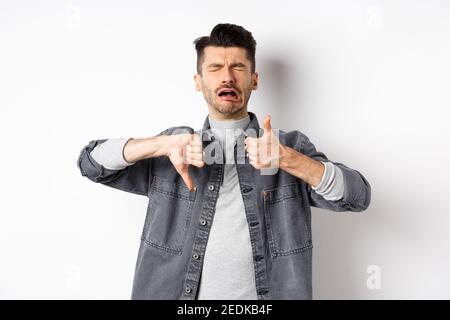 Sad man crying and showing thumbs up down, whining and complaining ...