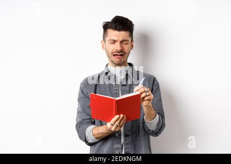Sad crying guy writing in his diary with miserable face, look ...