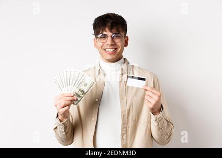 Happy person stands with money and plastic credit card. Young man ...