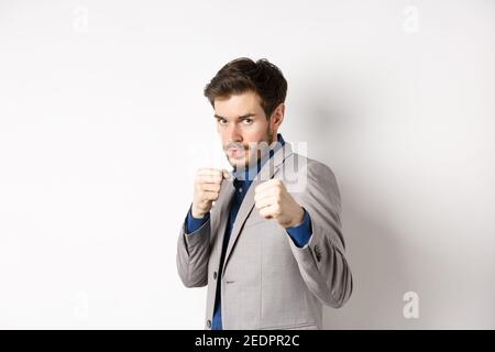 Serious man in suit raising hands in boxer pose, going to fight ...