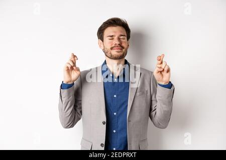 Nervous businessman in suit begging god, holding fingers crossed with ...