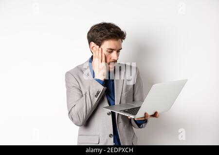 Shocked and worried businessman making mistake on laptop, looking at ...