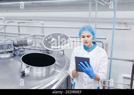 Female chemical plant process operator walkway to storage tank pipes ...