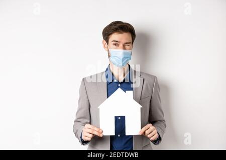 Real estate and covid concept. Cheerful guy in medical mask showing ...