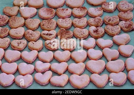 Pink heart homemade macaron cookies on parchment paper on a baking ...