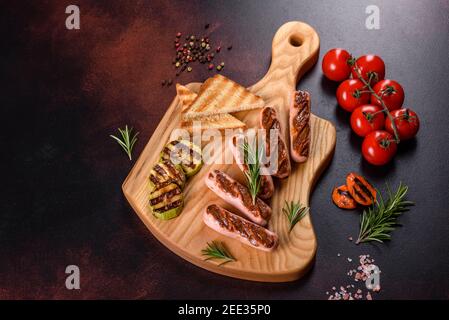 Grilled sausages with spices and herbs on a black background with copy ...