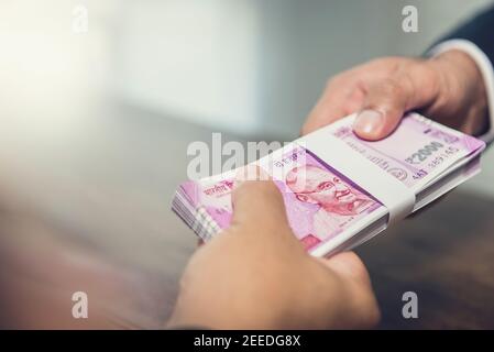Businessman giving money, Indian rupee currency, to hs partner ...