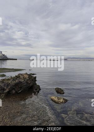 A vertical shot of rocks in the ocean under a blue sky Stock Photo - Alamy