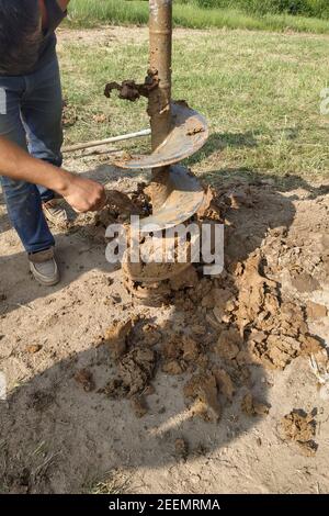 Workers are drilling pits for poles, starting work with a hand drill ...