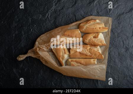Freshly baked bread slices on cutting board against white wooden ...
