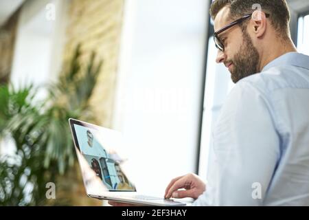 Contented businessman with laptop standing by building Stock Photo - Alamy
