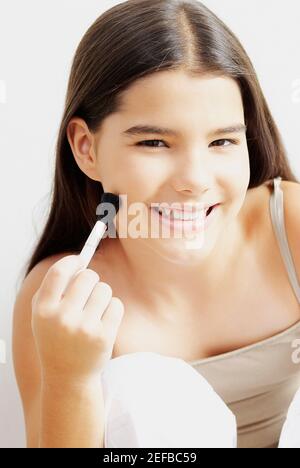 Portrait of a tween girl applying make-up on her cheek Stock Photo - Alamy