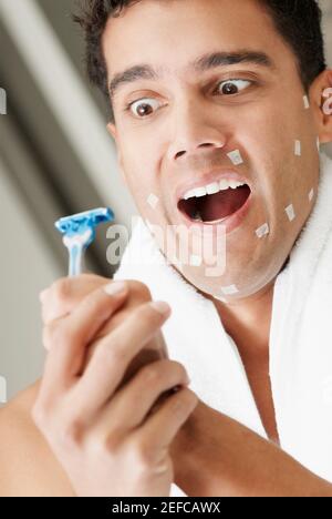 Young hispanic man holding razor smiling happy pointing with hand and ...