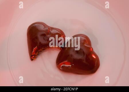 Heart-shaped plate with chocolate candies and rose flowers on turquoise ...