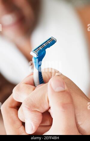 Young hispanic man holding razor pointing thumb up to the side smiling ...