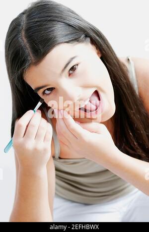 Portrait of a tween girl applying make-up on her cheek Stock Photo - Alamy