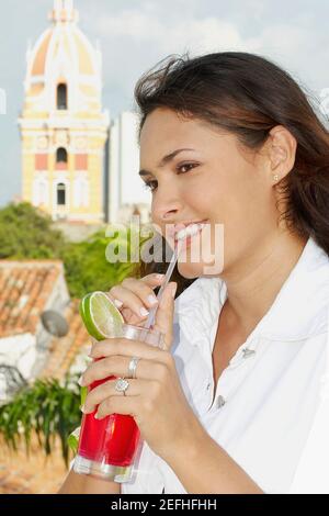 Young hispanic woman drinking glass of orange juice skeptic and nervous ...