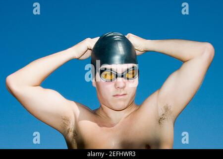 Young hispanic man wearing swimsuit and hawaiian lei drinking tropical ...