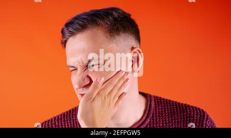 Man getting slapped on orange background. Unhappy scared man getting ...