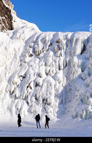 A group of three people at the frozen Chutes de Chaudière at Charny ...