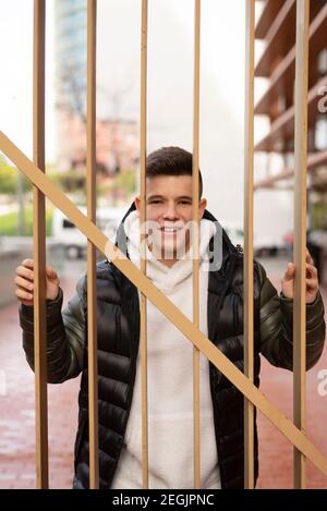 Young guy standing behind a metal fence while looking camera Stock ...