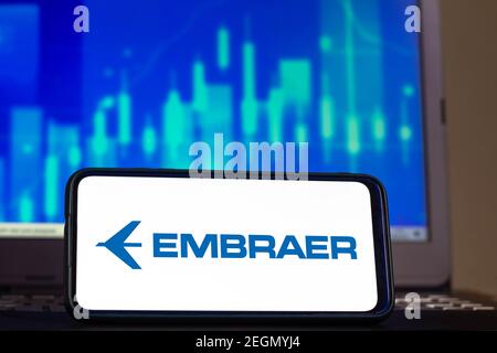 In this photo illustration, Embraer logo seen on a smartphone and a pc ...