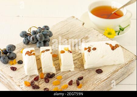 Sliced halva with nuts and dried fruits on a plate served with flowers ...