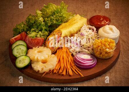 Shawarma with meat, vegetables, cheese and pineapple on a wooden ...