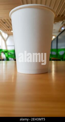 Cup of coffee to go on the wooden table. Street coffee, blurred ...