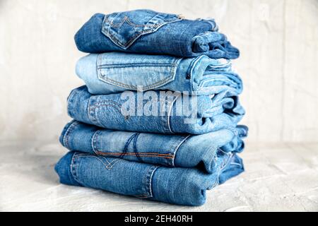 stack of blue jeans on a gray background Stock Photo - Alamy